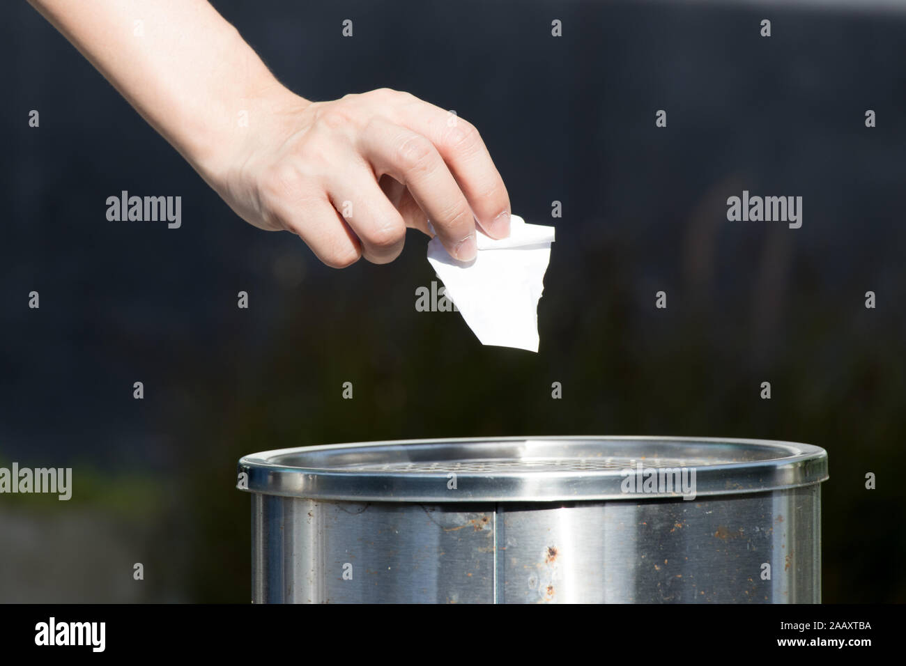 Female hand pick the paper scrap into the metal garbage bin background ...