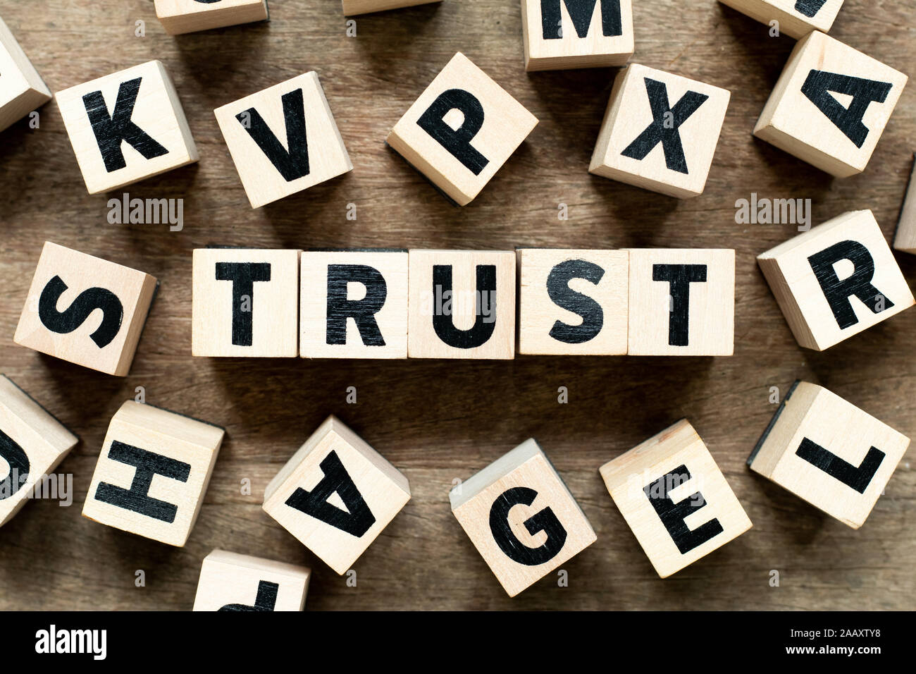 Letter block with word trust on wood background with another alphabet ...