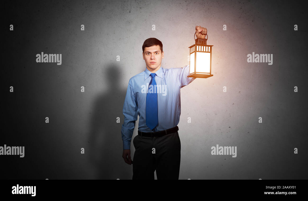 Scared businessman holding glowing lantern Stock Photo - Alamy