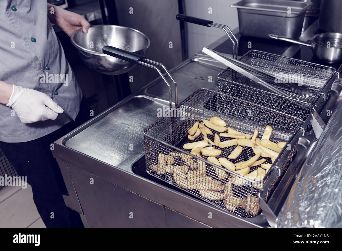 Chef is cooking french fries at commercial kitchen, toned Stock Photo ...