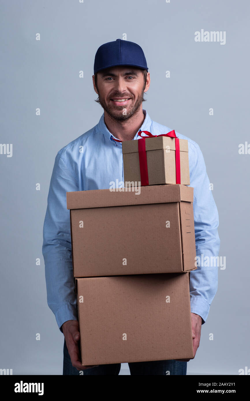 Happy smiling delivery man in uniform cap holding box stack Stock Photo ...