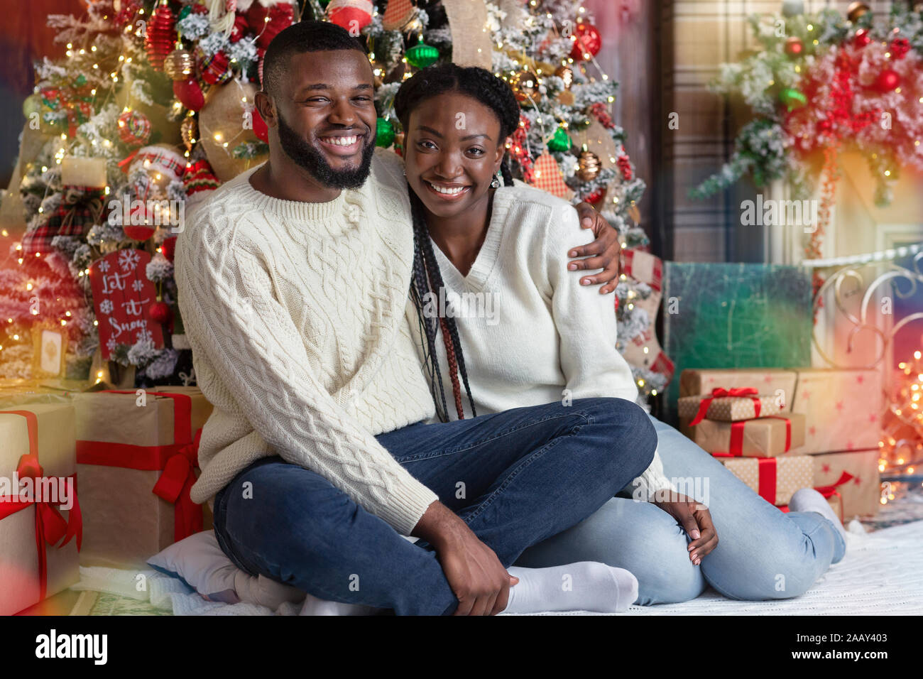 Cheerful black couple posing near Christmas tree, celebrating Christmas ...