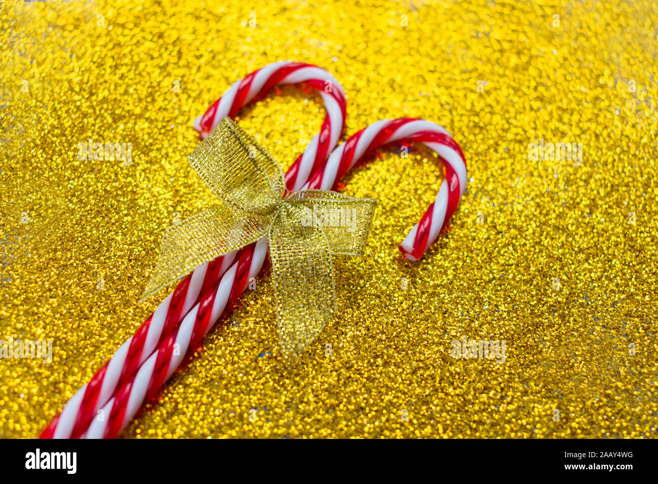 Two christmas candies with a golden bow on a shiny gold background ...