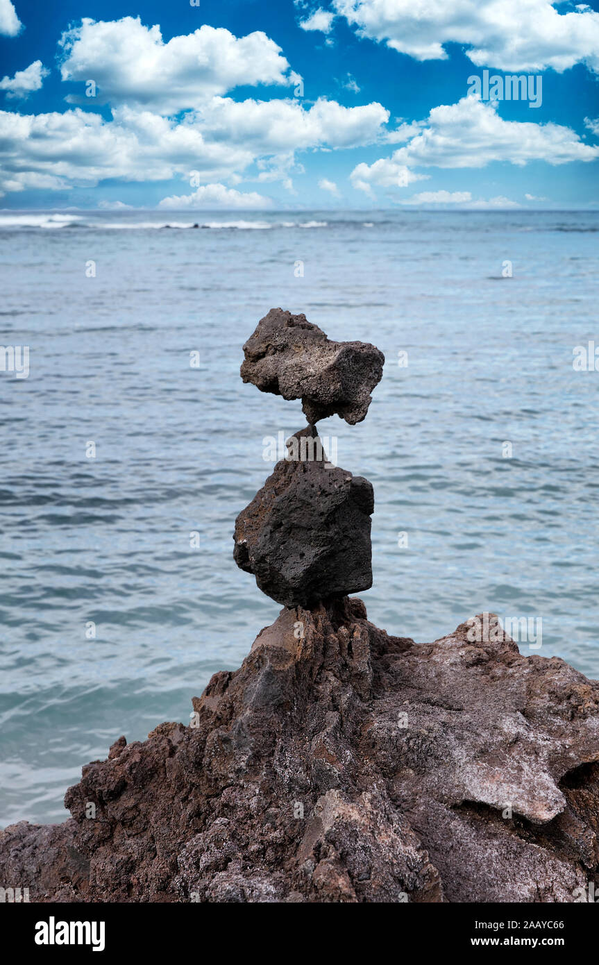 Native rocks stacked vertically with ocean and blue sky in background ...