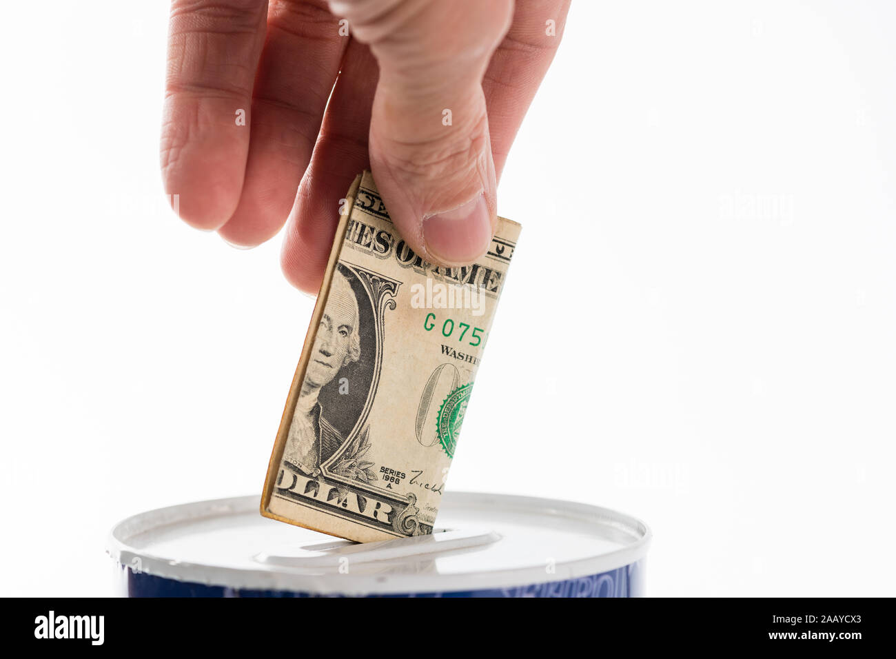 Male hand putting dollar bill into tin can saving bank on white ...