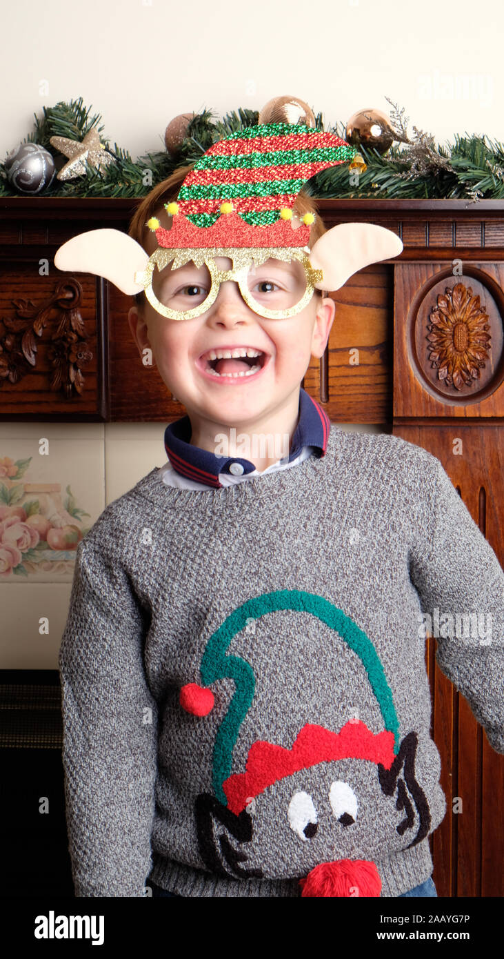 A young boy wearing a festive Christmas mask and smiling at the camera ...