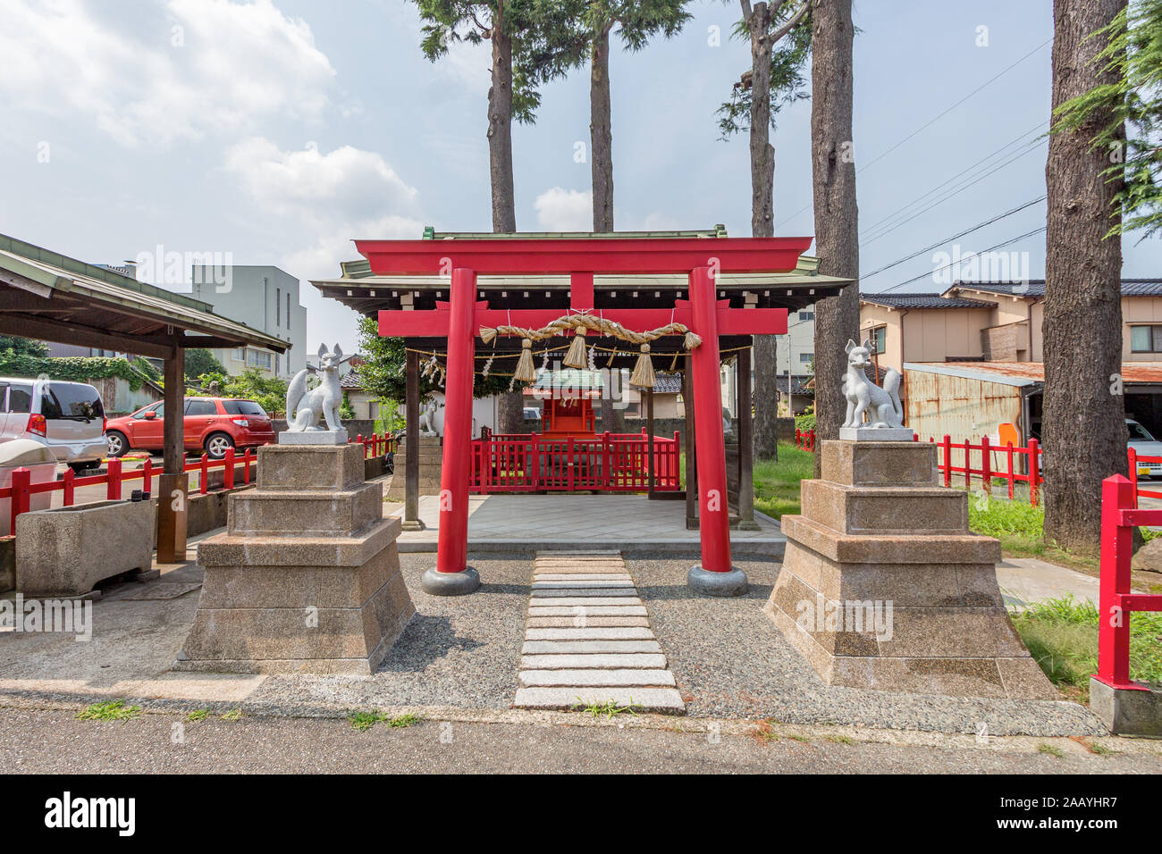 Torii gate and historic stone statues of foxes, or kitsune in Japanese ...