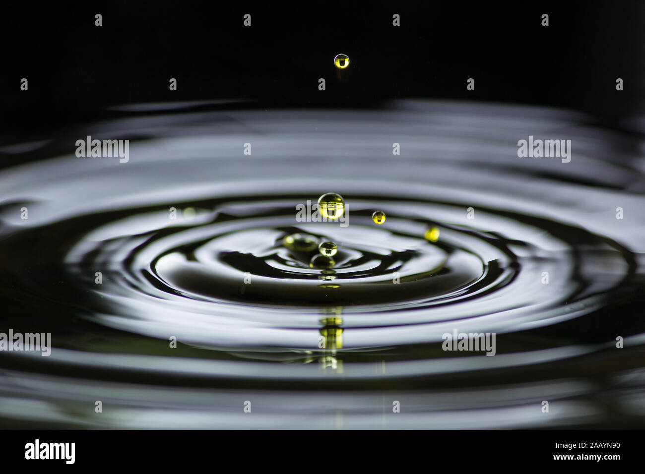 golden Droplets in dark shaded water Stock Photo - Alamy