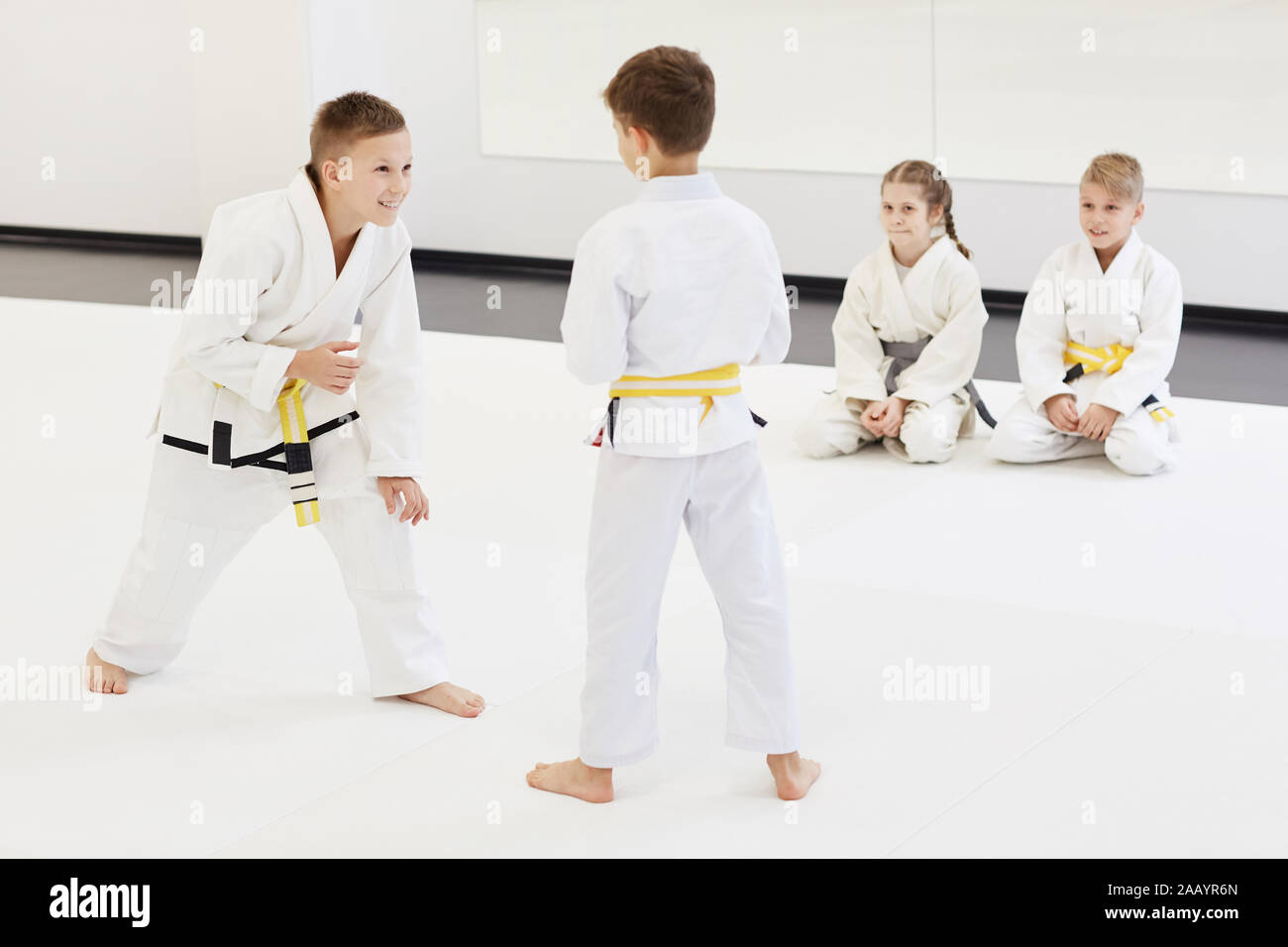 Two boys in kimono standing and practicing technique in karate while ...