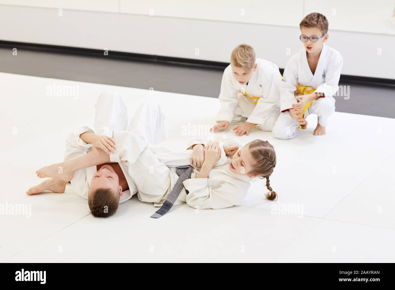 Girl fighting with boy on the floor while other children cheering for ...