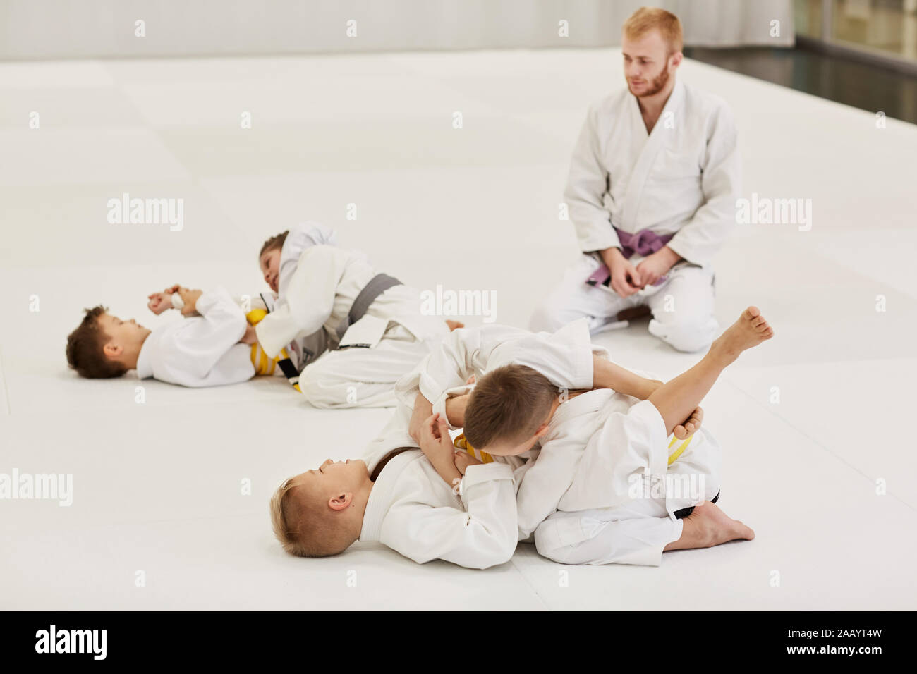 Group of children fighting with each other on the floor with coach ...