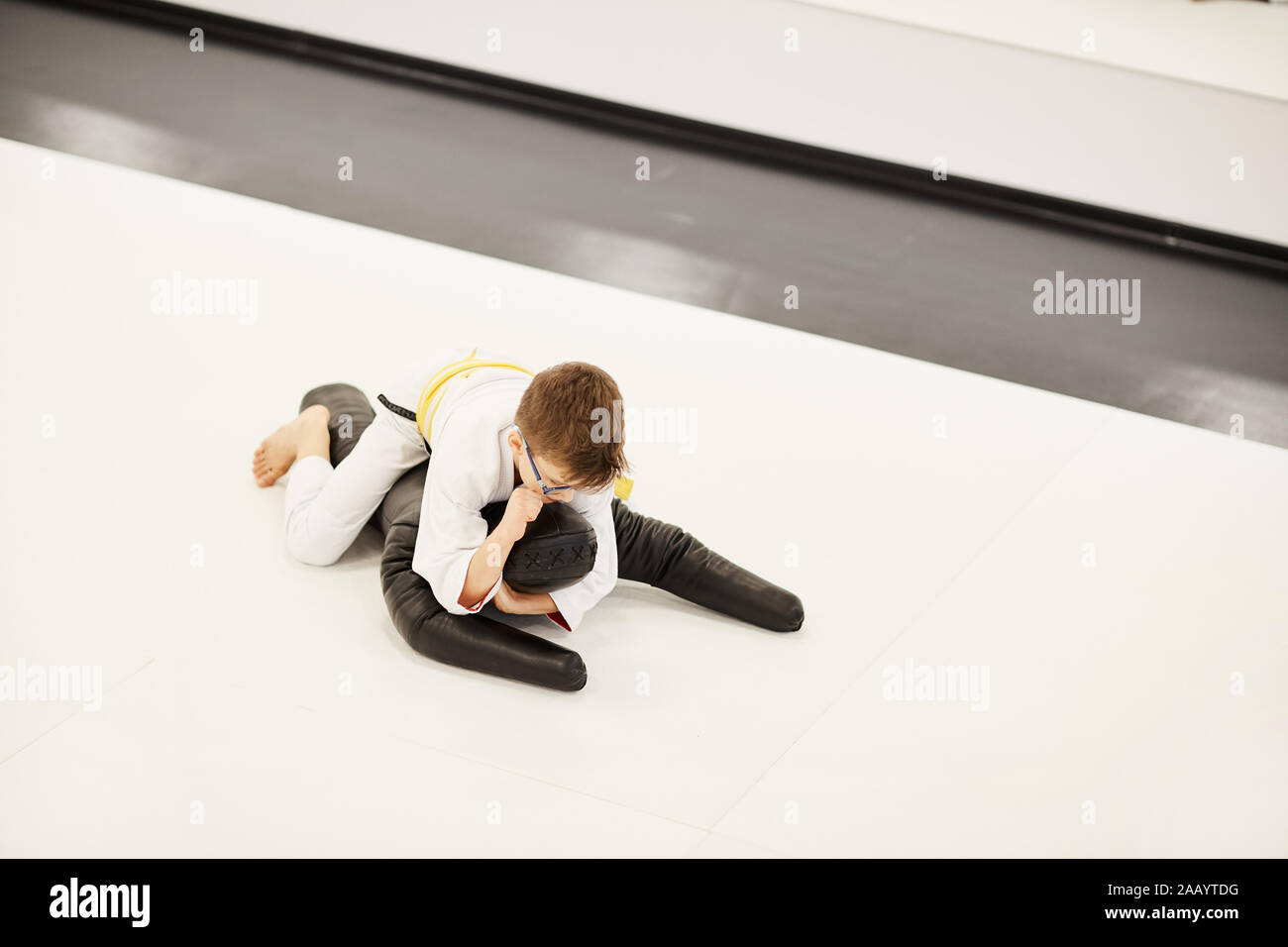 Little boy in kimono lying on the floor and fighting with mannequin ...