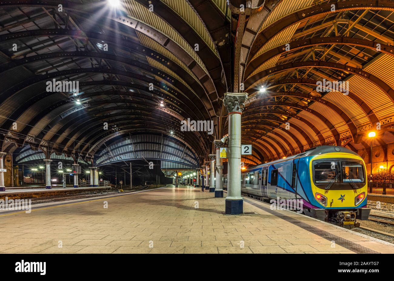York Railway Station at night. A train waits as lights shine onto an ...
