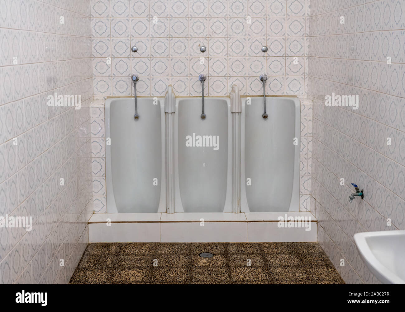 Set of three side by side full length mens urinals in porcelain against ...