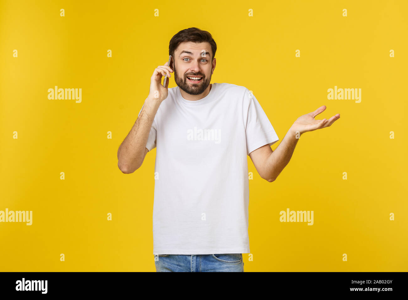 Portrait of a serious man talking on the phone isolated on a yellow ...