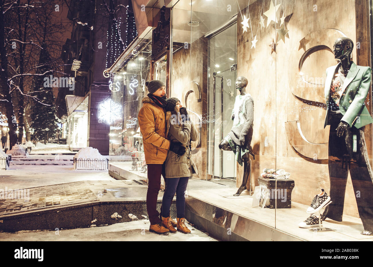 Young couple walking in the city center and window-shopping at night ...