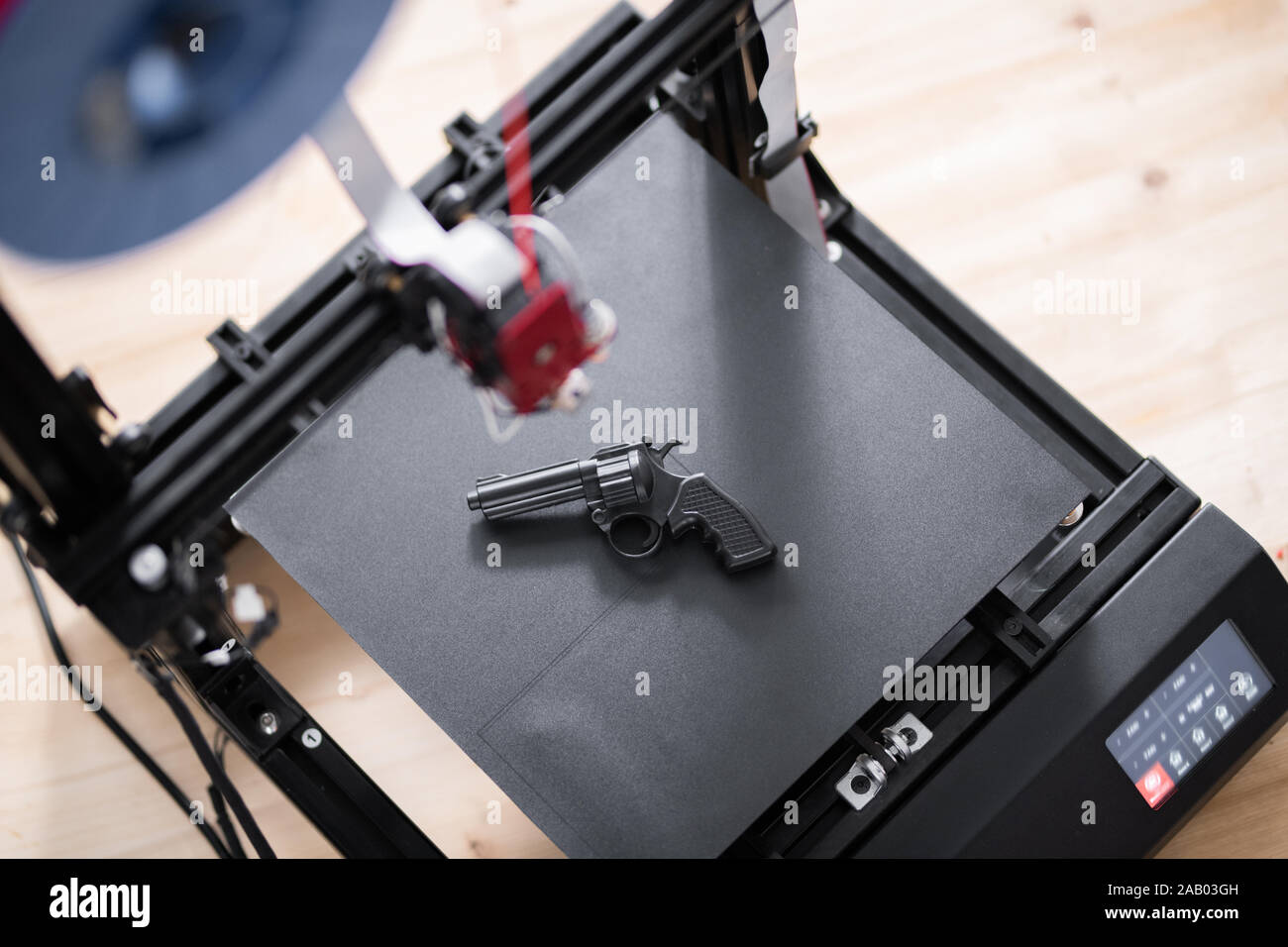 Overview of black revolver gun on working surface of 3d printer on ...