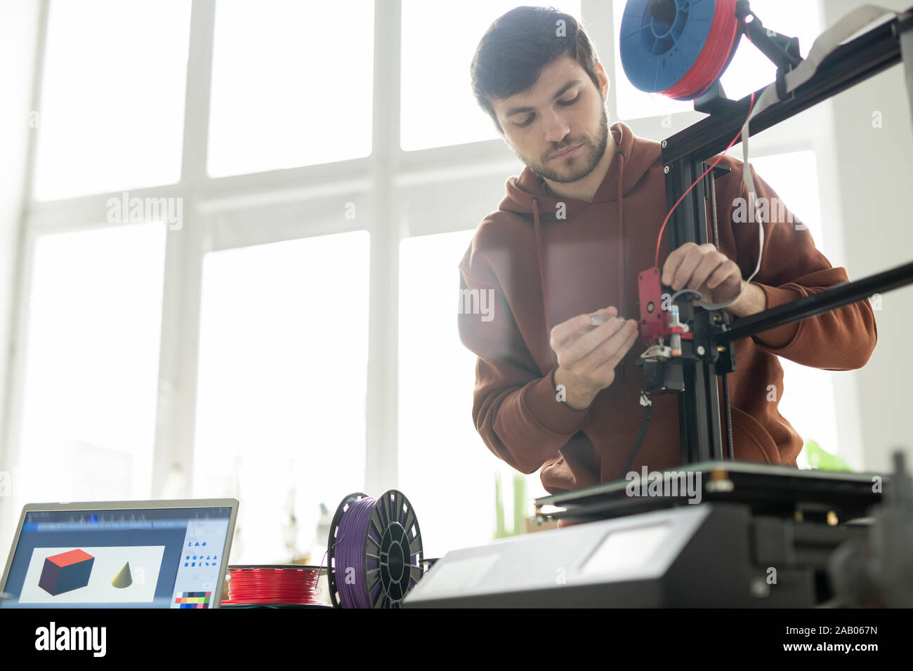 Young technician repairing or changing printhead while fixing its ...
