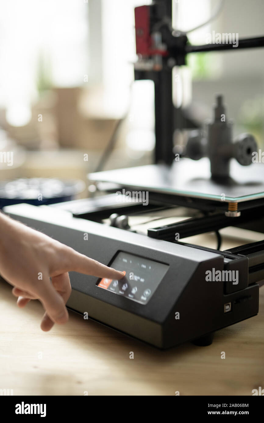 Hand of young designer pressing start button on control panel of 3d ...