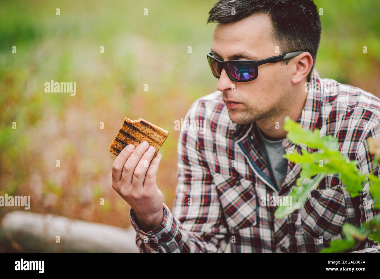 Hungry man eating. Sandwich outdoors. hiker eating sandwich sitting in ...