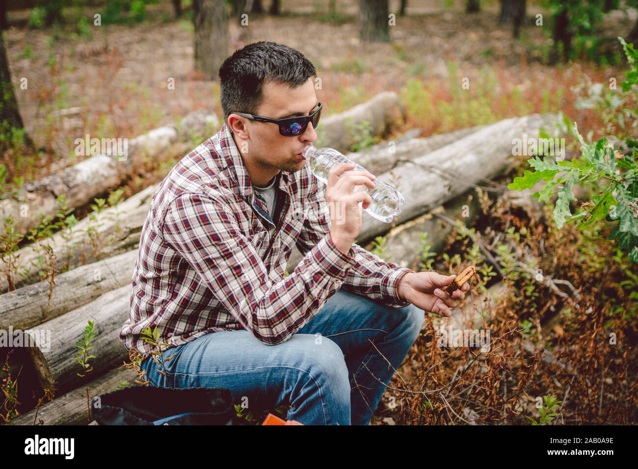 Fast food theme snack on nature. Caucasian man eating a sandwich and ...