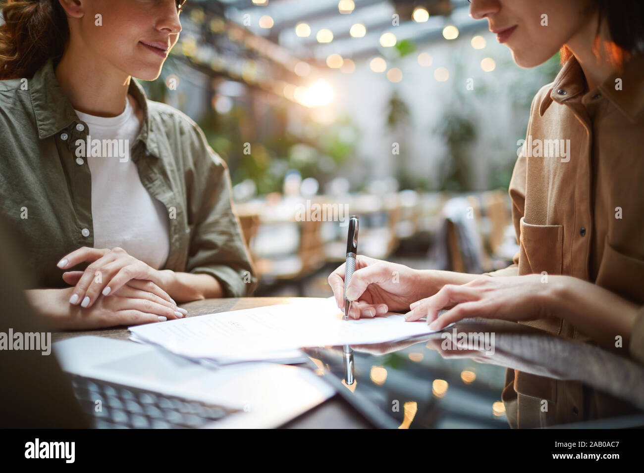 Close up of unrecognizable young woman signing contract during business ...