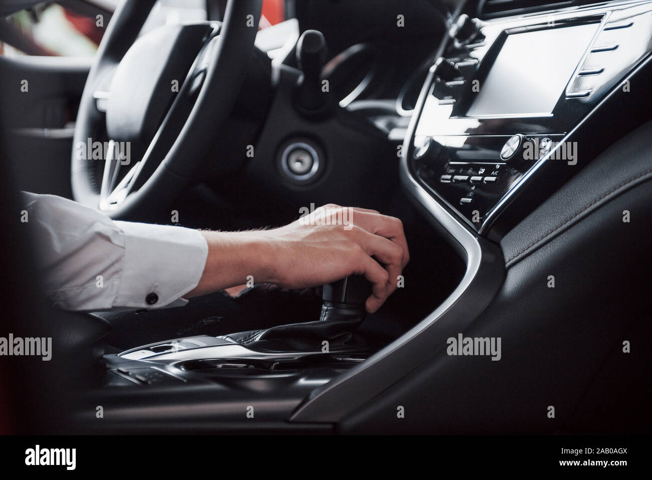 Close up of a young man driving a road car holding his hand on a ...