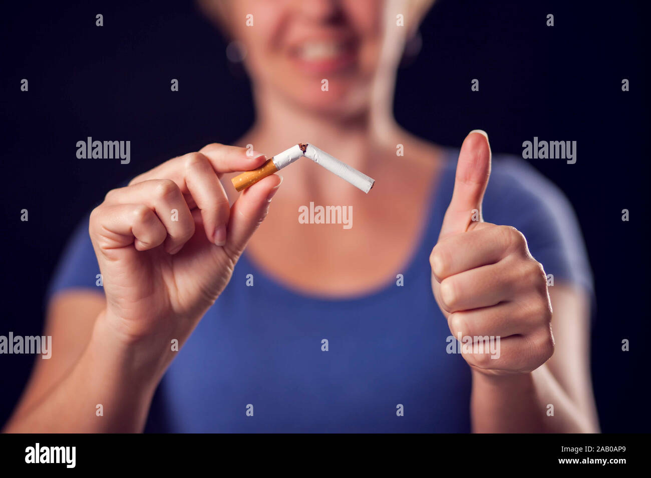 Woman in a blue t-shirt holding broken cigarette in hands. Stop smoking ...