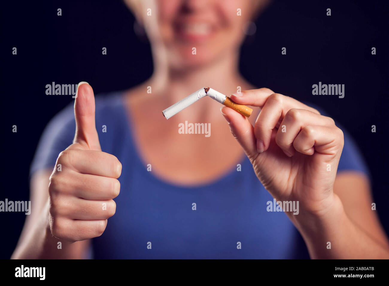 Woman in a blue t-shirt holding broken cigarette in hands. Stop smoking ...