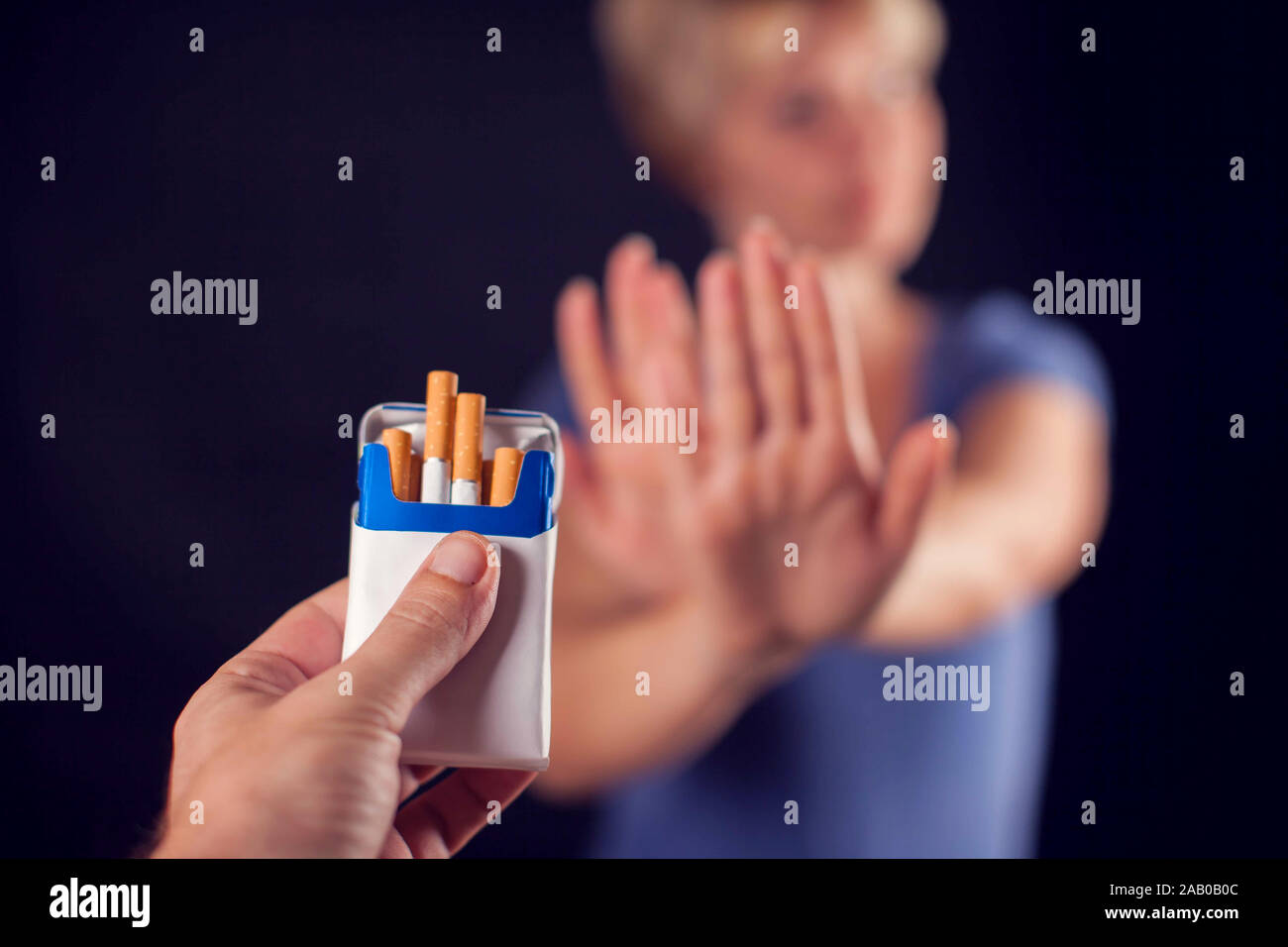 Woman in blue t-shirt refusing cigarettes on black background. Stop ...