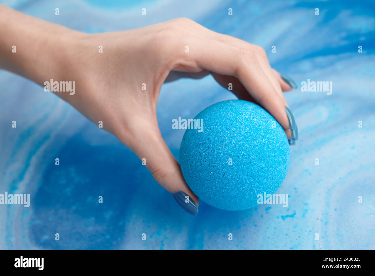 Woman's hand putting blue bath bomb into water, copy space Stock Photo ...