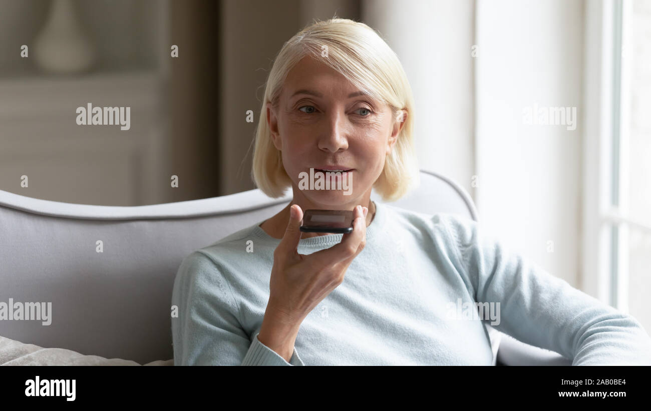 Elderly Woman Holding Smartphone Uses Virtual Voice Assistant Stock