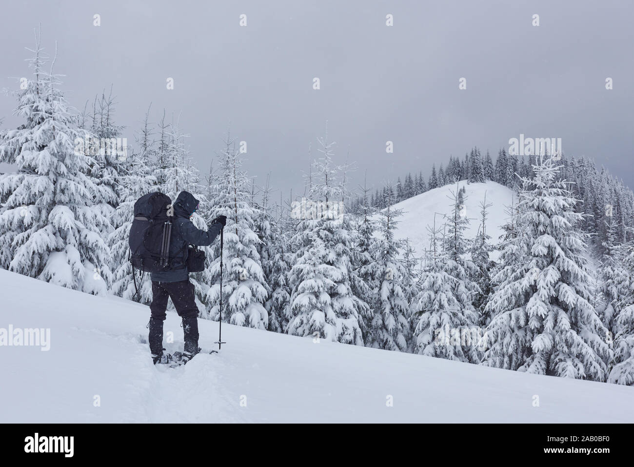 Hiker, with backpack, is climbing on the mountain range, and admires ...