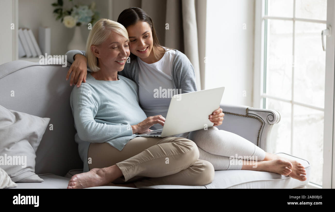 Mother and grownup daughter resting on couch with computer Stock Photo ...