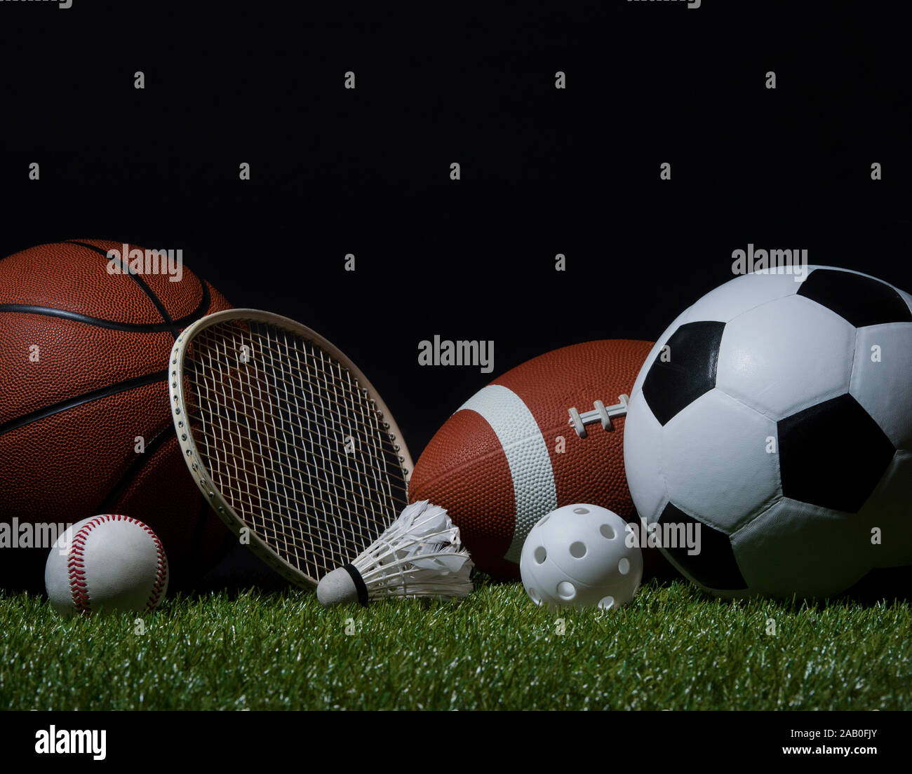 Sports equipment, rackets and balls on green grass with black ...