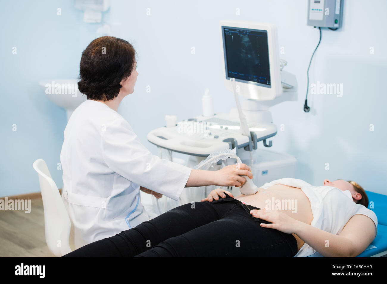 Happy mature female doctor using ultrasound scanner. Echography machine ...