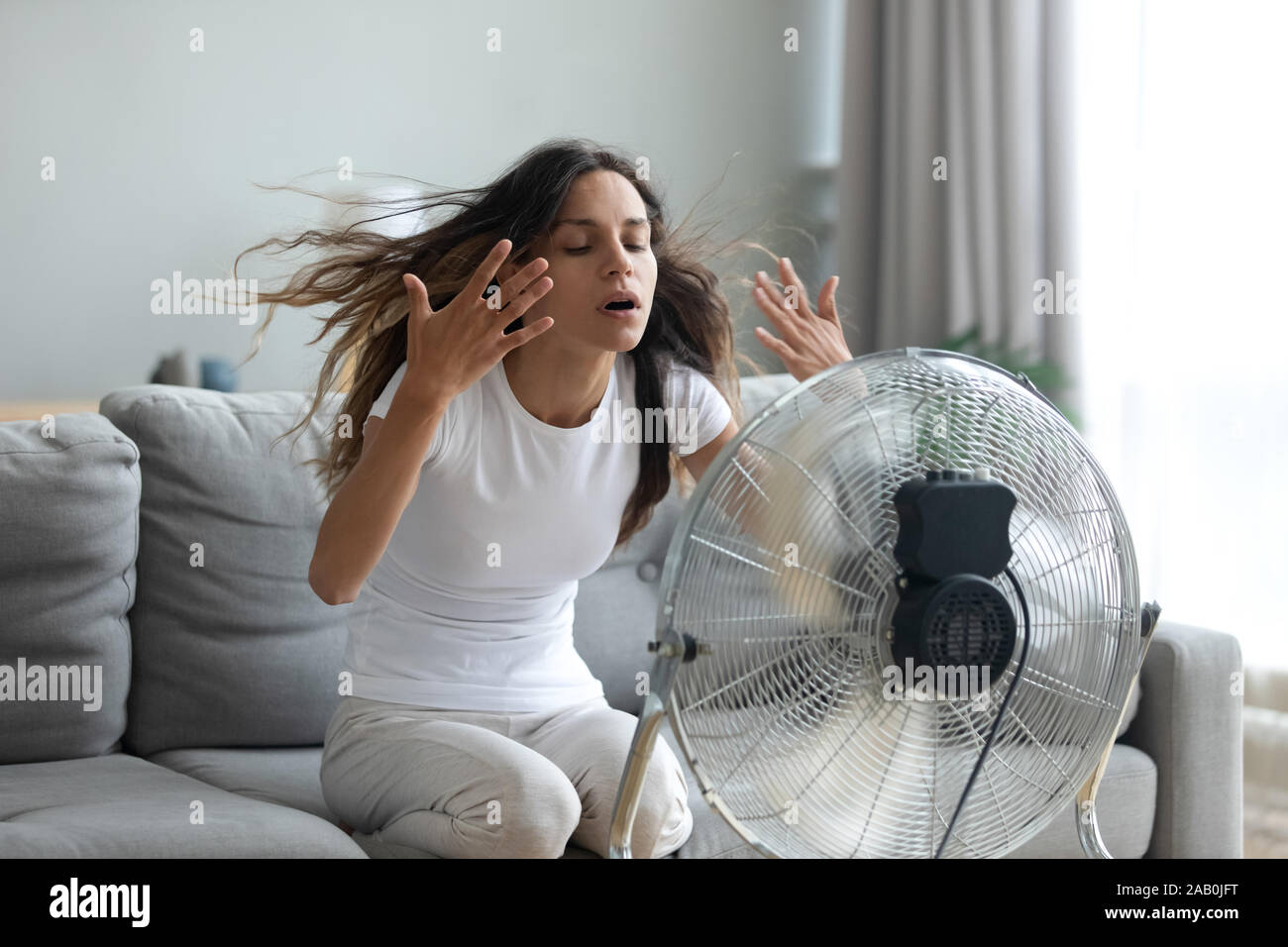 Woman turned on fan waving her hands to cool herself Stock Photo - Alamy
