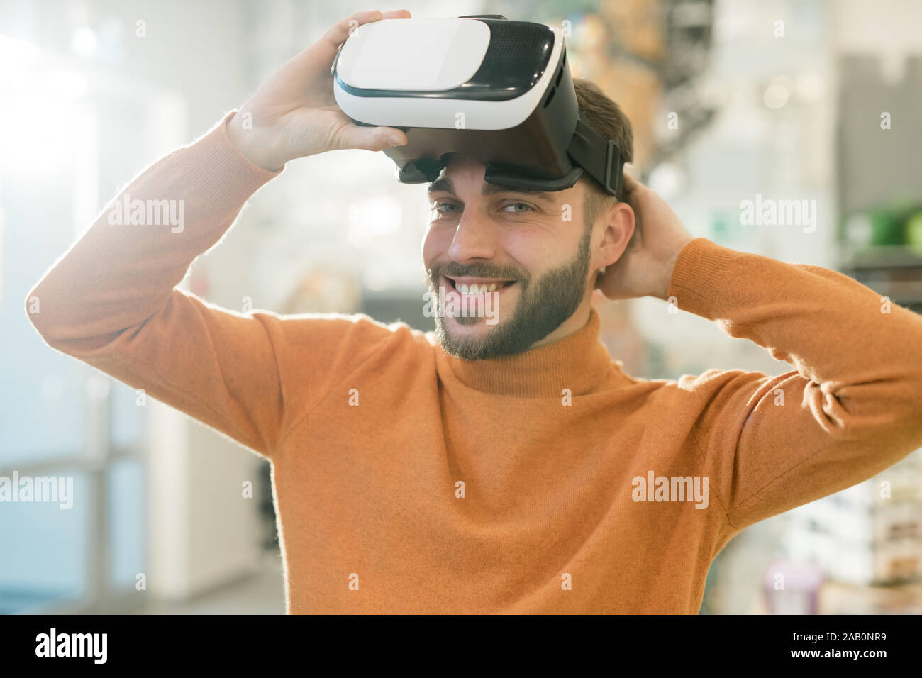 Happy young man looking at you with smile while taking off vr headset ...