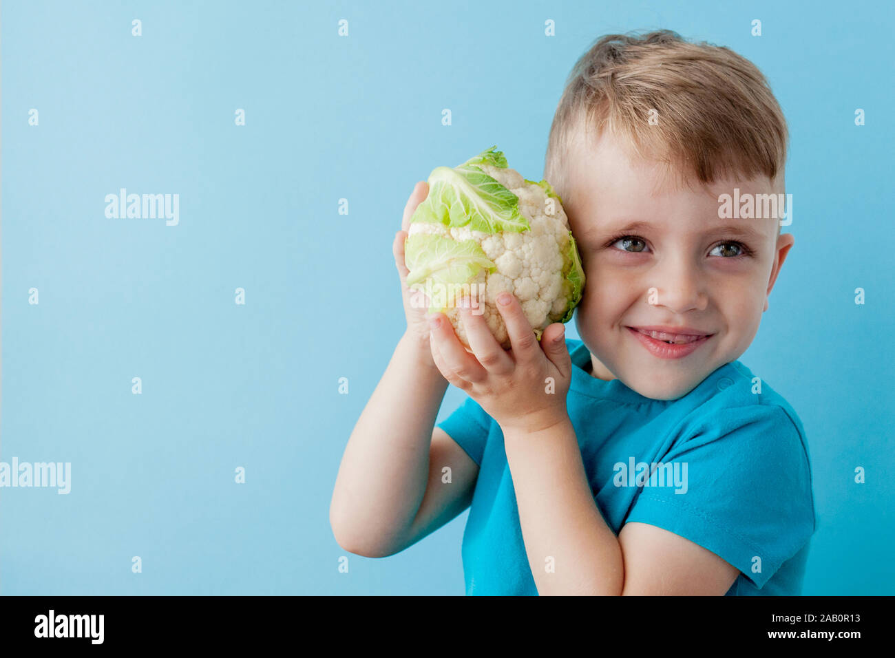 Little Boy Holding Broccoli in his hands on blue background, diet and ...