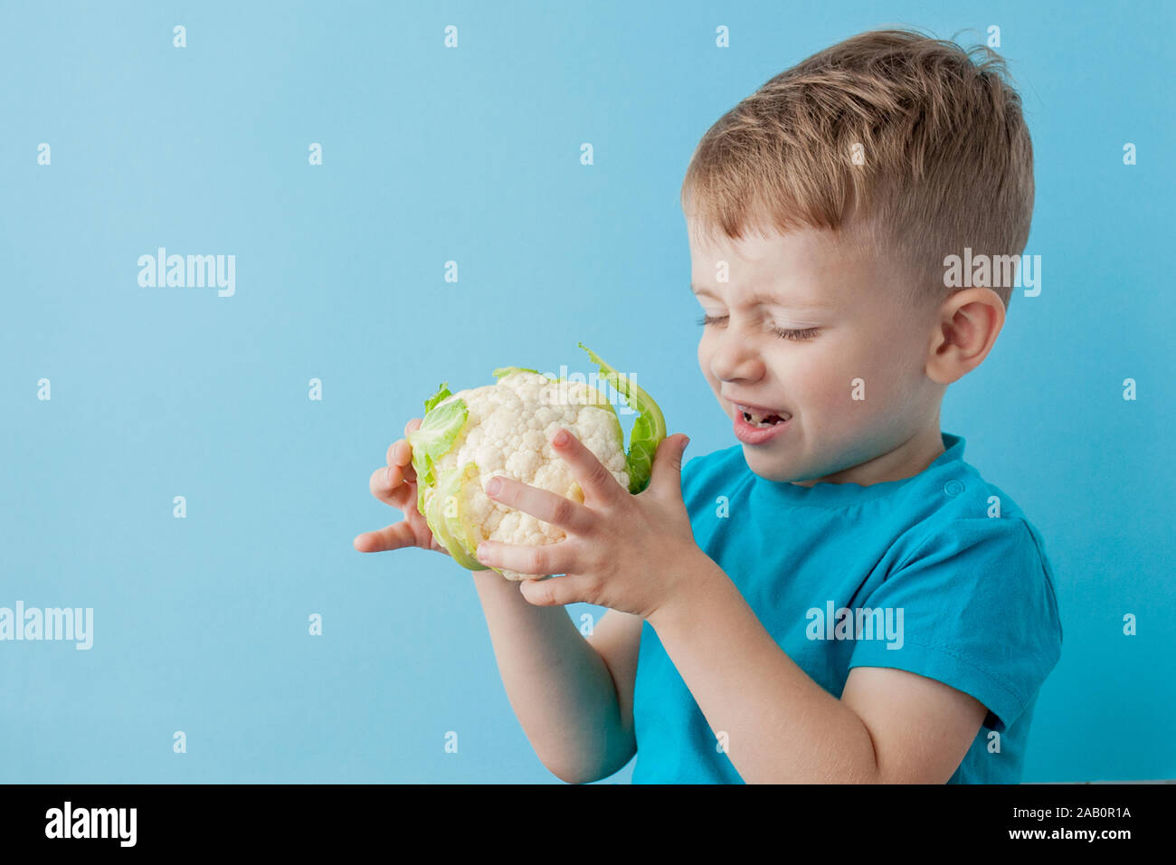 Little Boy Holding Broccoli in his hands on blue background, diet and ...