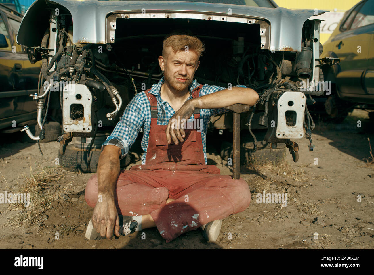 Male mechanic poses on car junkyard Stock Photo - Alamy