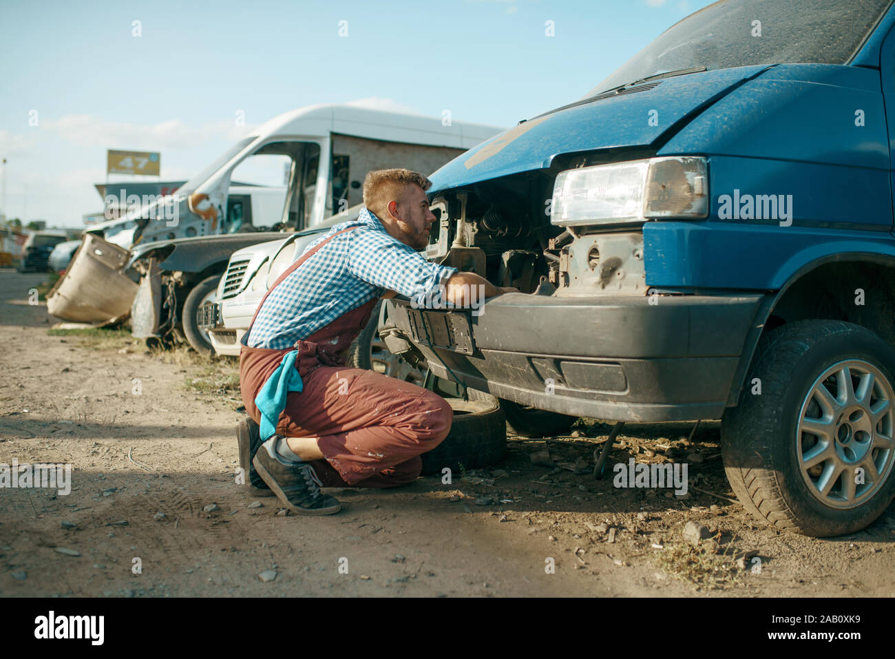 Mechanic stuck head under the hood, car junkyard Stock Photo - Alamy
