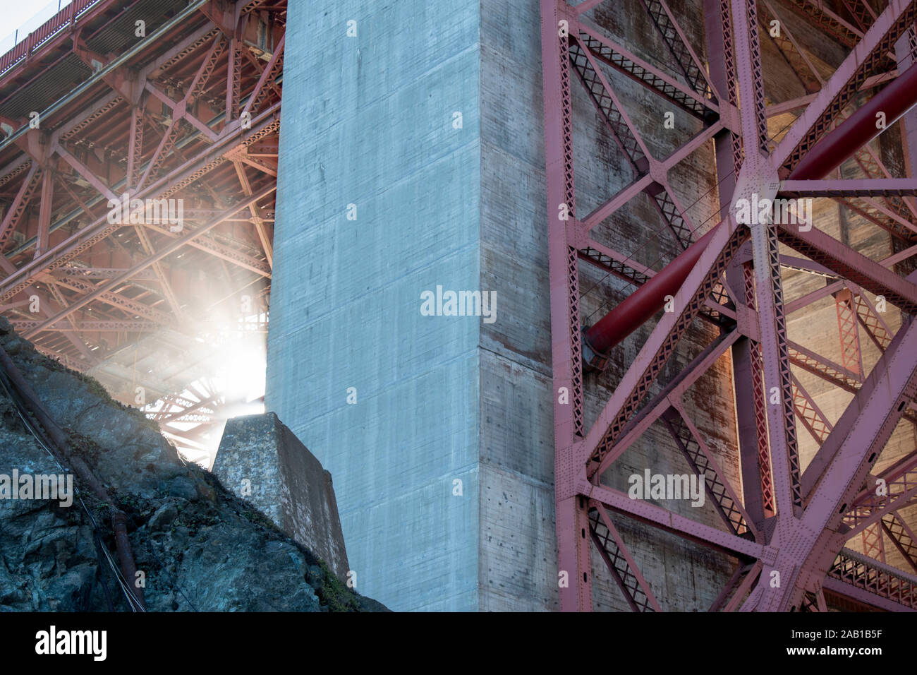 Sun rays peek around some of the supports of the Golden Gate Bridge ...