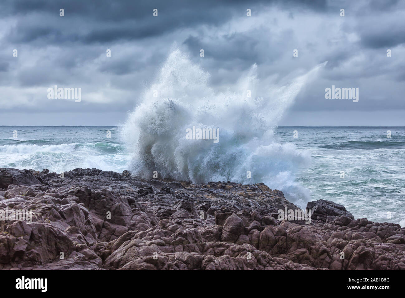 Wave crashing over person standing on rocks Stock Photo - Alamy