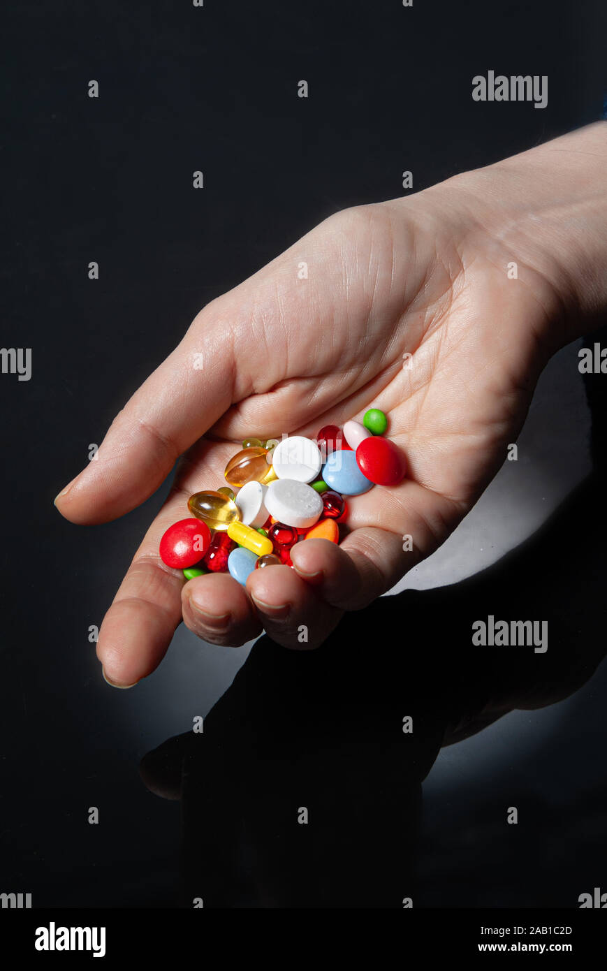 Different coloured drugs in a woman's hand on a glass background Stock ...