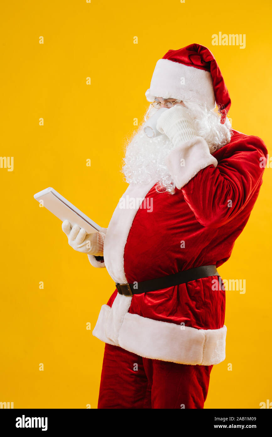 Santa Claus checking his order list while drinking hot coffee Stock ...