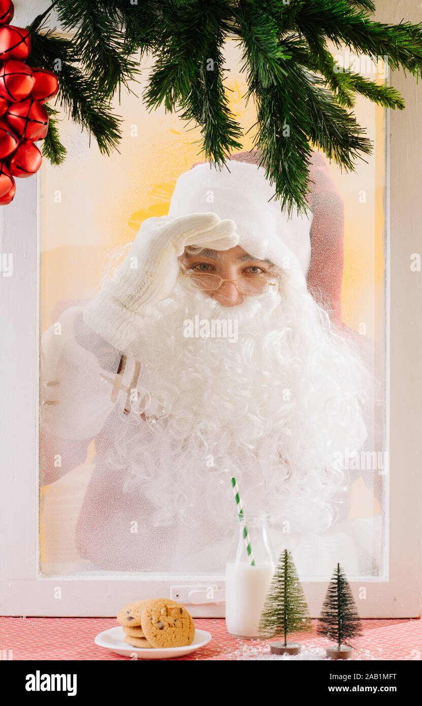 Santa Claus looking inside a home from the other side of the window ...
