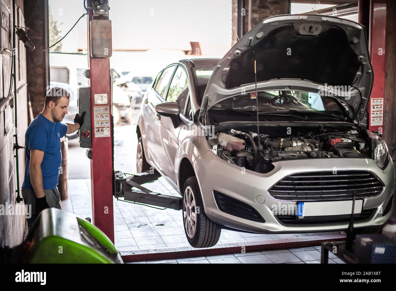 Car mechanic working in a repair garage with hydraulic car lift ...