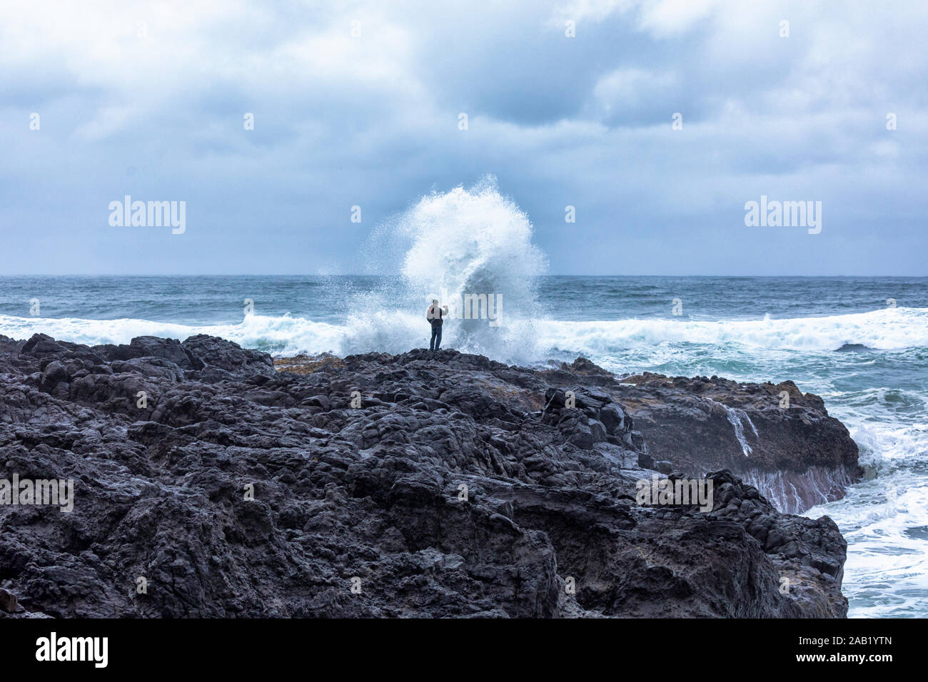 Wave crashing over person standing on rocks Stock Photo - Alamy