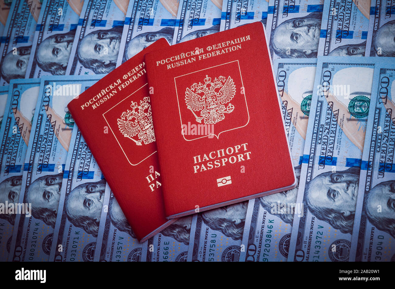 Two red passport on the background of hundred dollar bills. Blue design ...